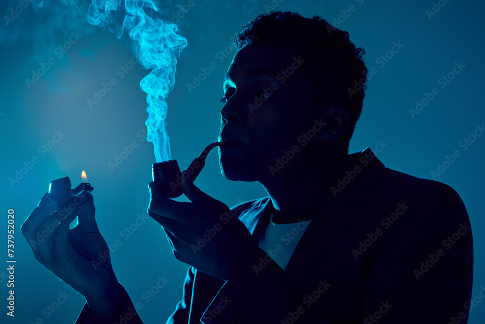 young african american guy holding lighter and pipe while exhaling ...