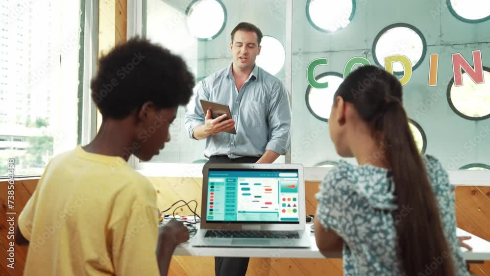 Vidéo Stock Smart teacher hold tablet while back view student learning engineering code on table ...