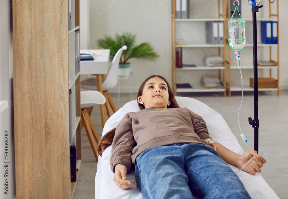 Teenage child girl lying on the couch in the clinic while receiving IV ...
