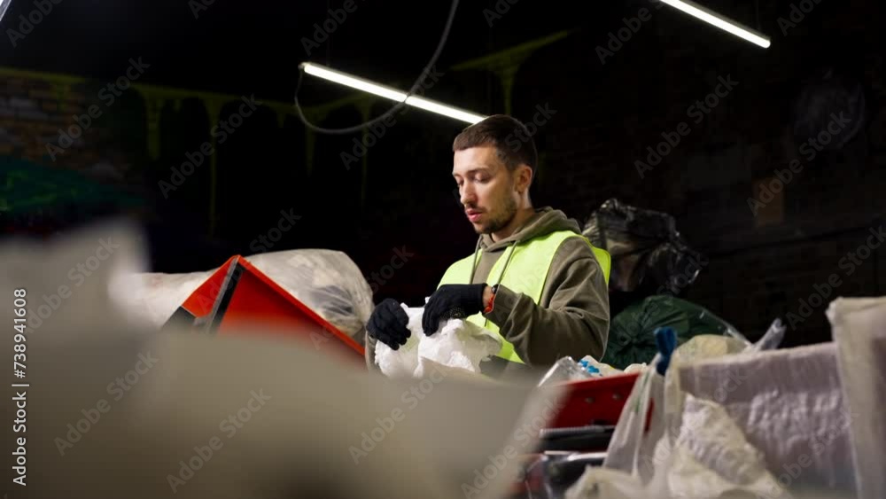 portrait of concentrated male worker in gloves and safety vest sorting ...
