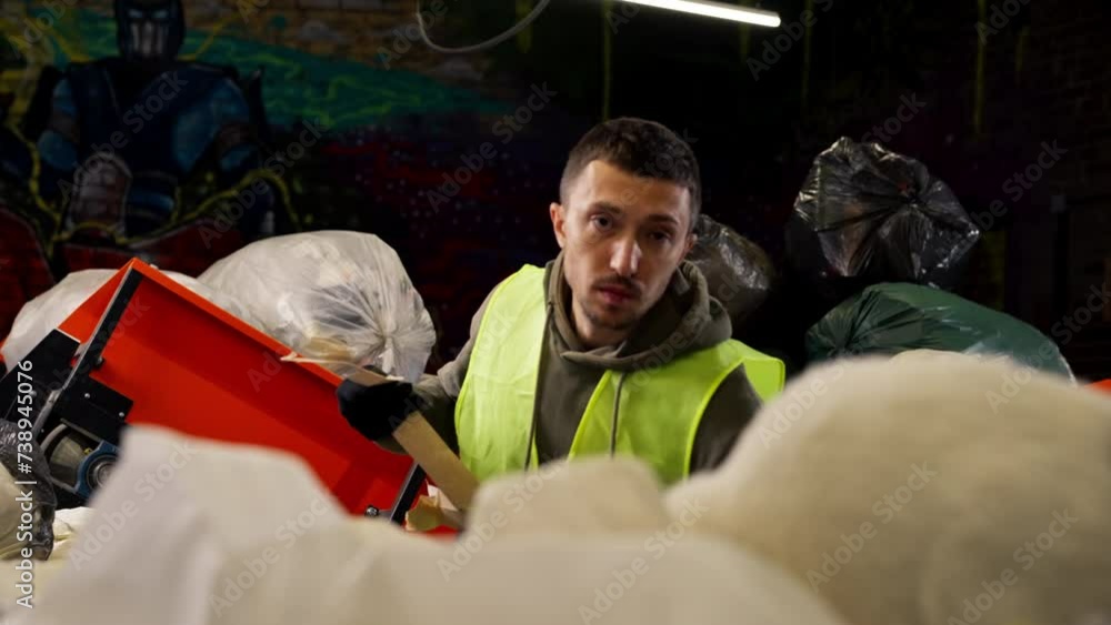 portrait of concentrated male worker in gloves and safety vest sorting ...