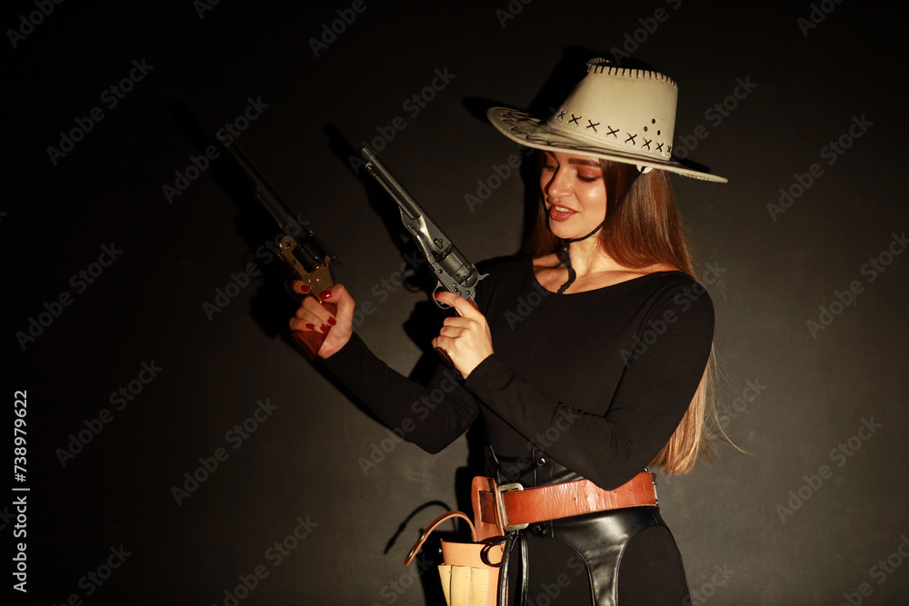 Beautiful young woman in white hat with two old revolvers low key ...