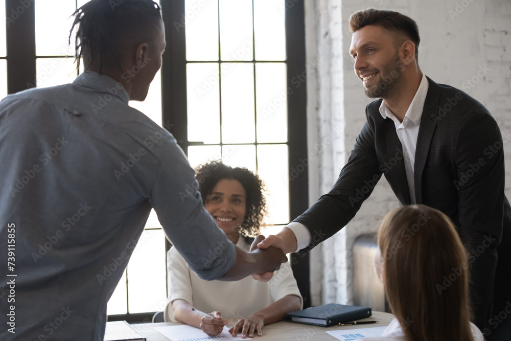 Friendly business partners shaking hands in negotiation meeting after ...