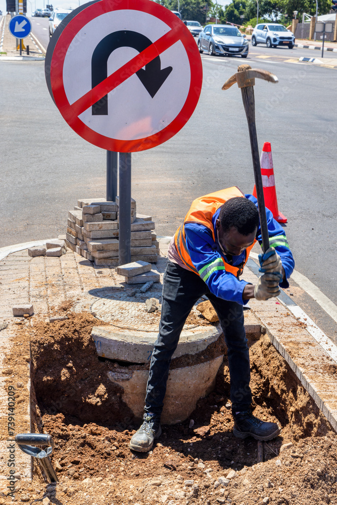african american worker with a pickaxe digging a ditch in the highway ...