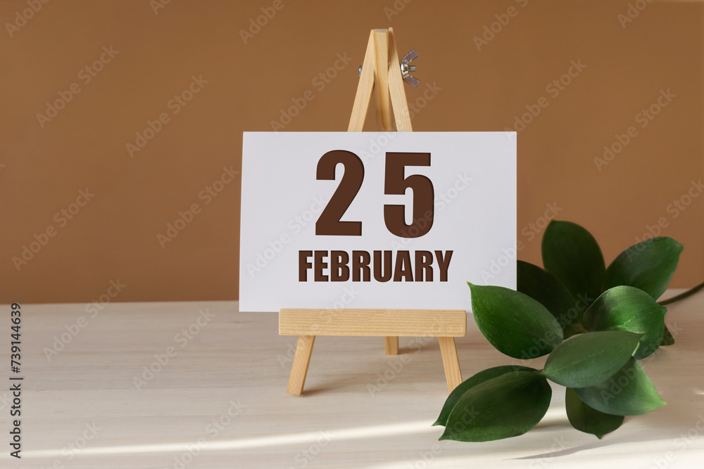 February 25th. Day 25 of month, Calendar date. Green branch, easel with ...