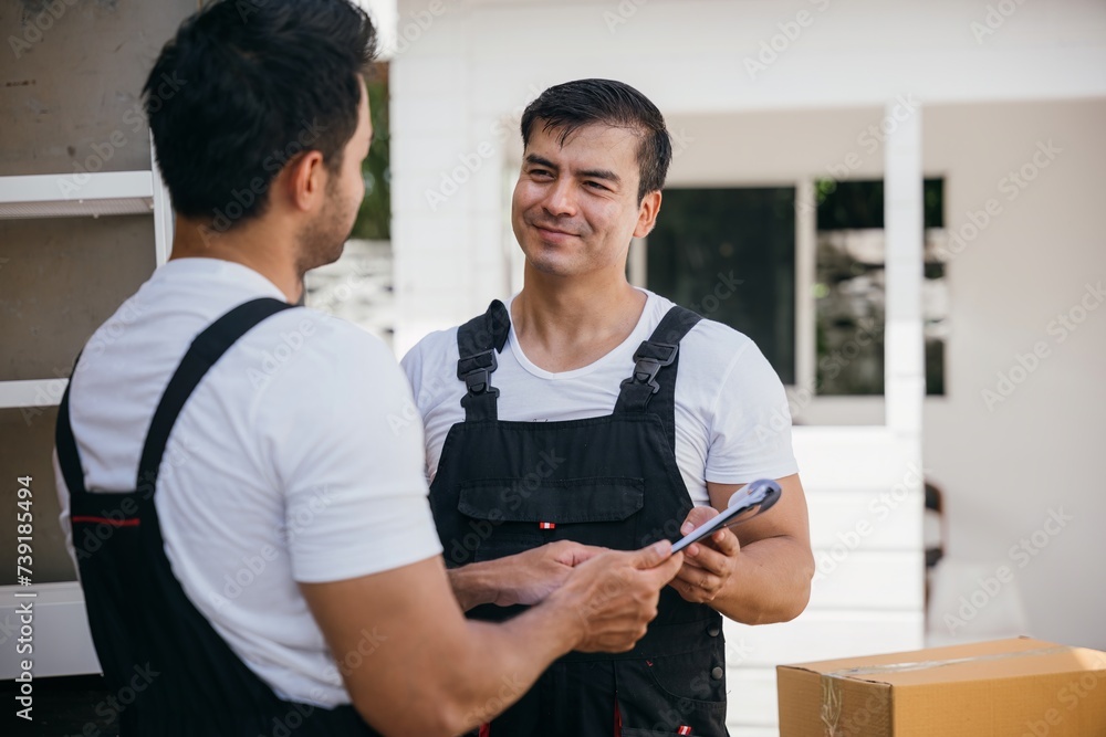 Moving service workers outdoors unloading boxes and checking list for ...
