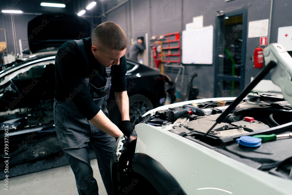 At a service station a master auto mechanic inserts the front part of ...