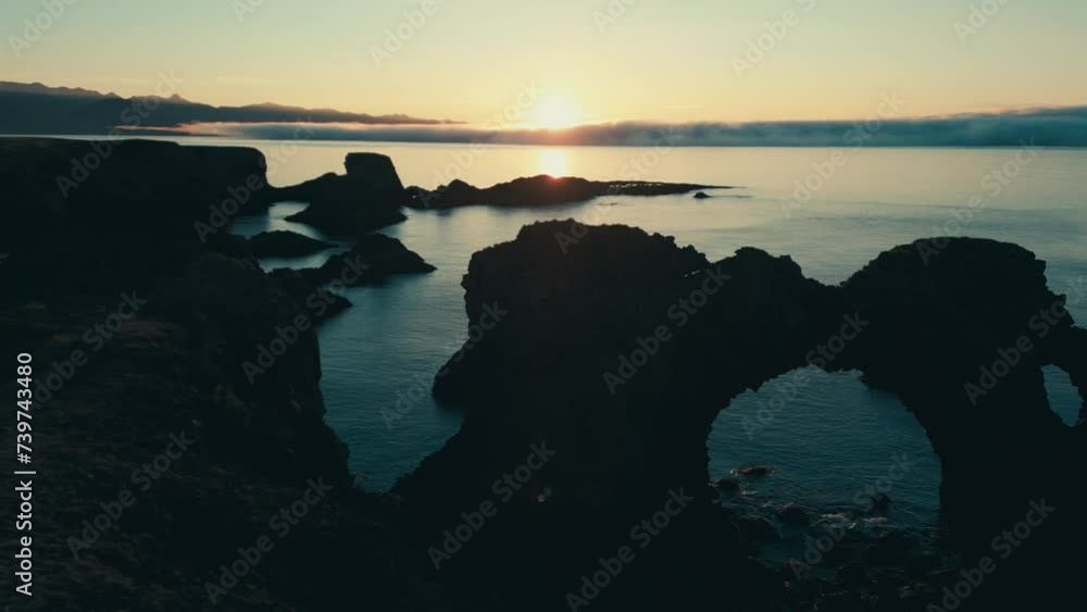Incredible drone aerial of coral sea arch and coastal lands during sunset. Gatklettur. Hellnar ...