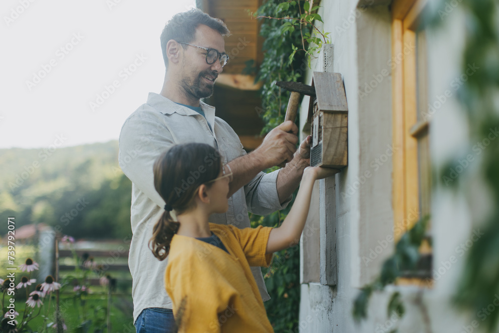 Father with daughter making bug hotel, or insect house outdoors in the ...