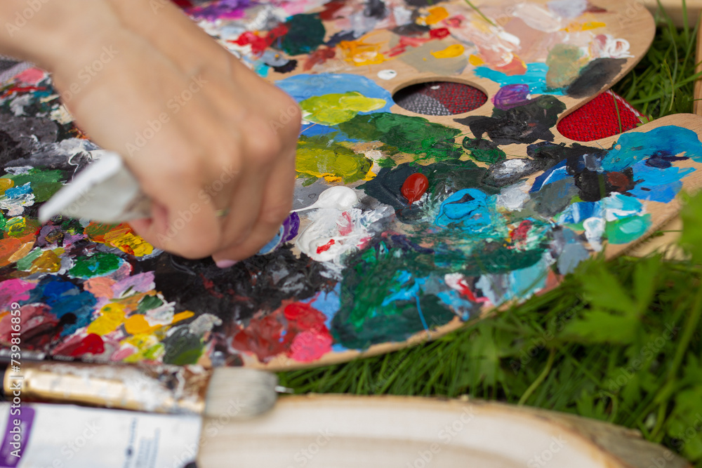 Oil color palette and human hand holding and pressing tube of paint ...