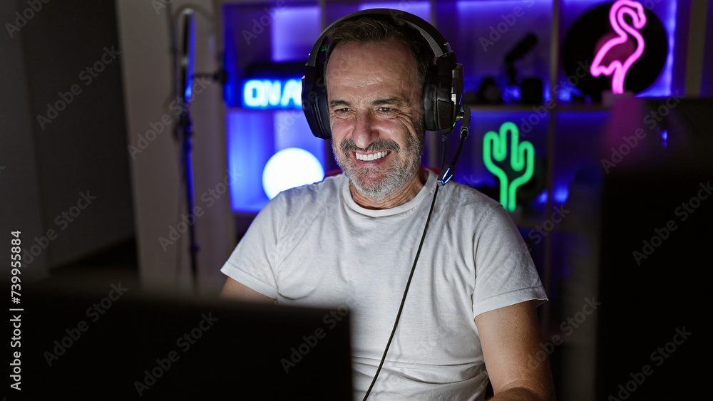 Confident middle-aged gamer with grey hair joyfully streaming his ...