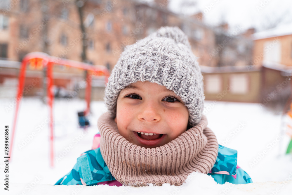 Smiling child with a woolly hat and scarf enjoying a snowy day at the ...