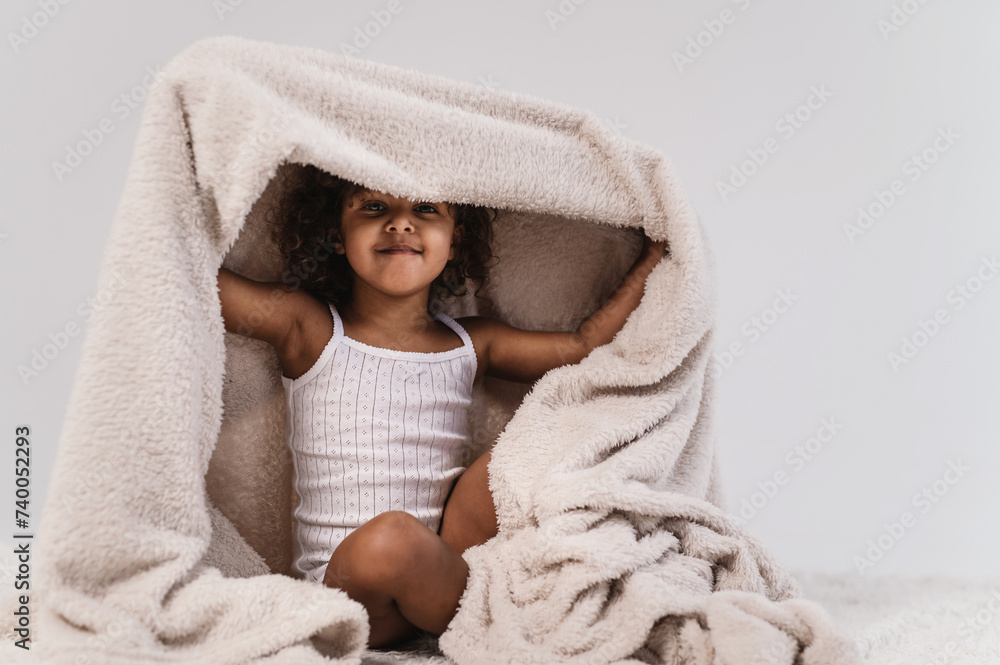 A little cute dark-skinned girl 2 years old plays with a fluffy white ...