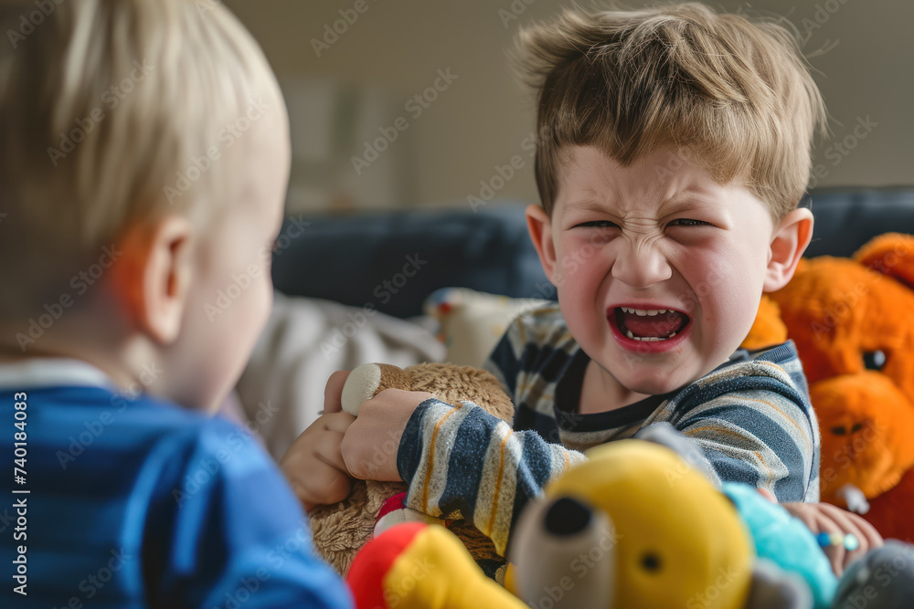 child refusing to share his toys with his sibling. He is holding onto ...