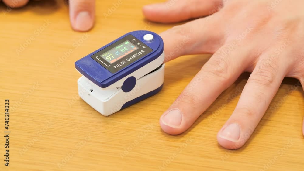 Human hand pulse oximeter used to measure pulse rate and oxygen levels ...