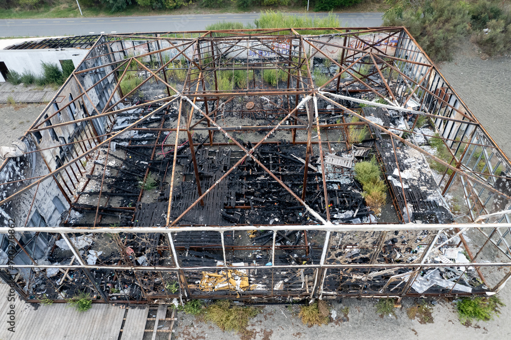 Metal and wooden remains after a fire of an establishment on the sand ...