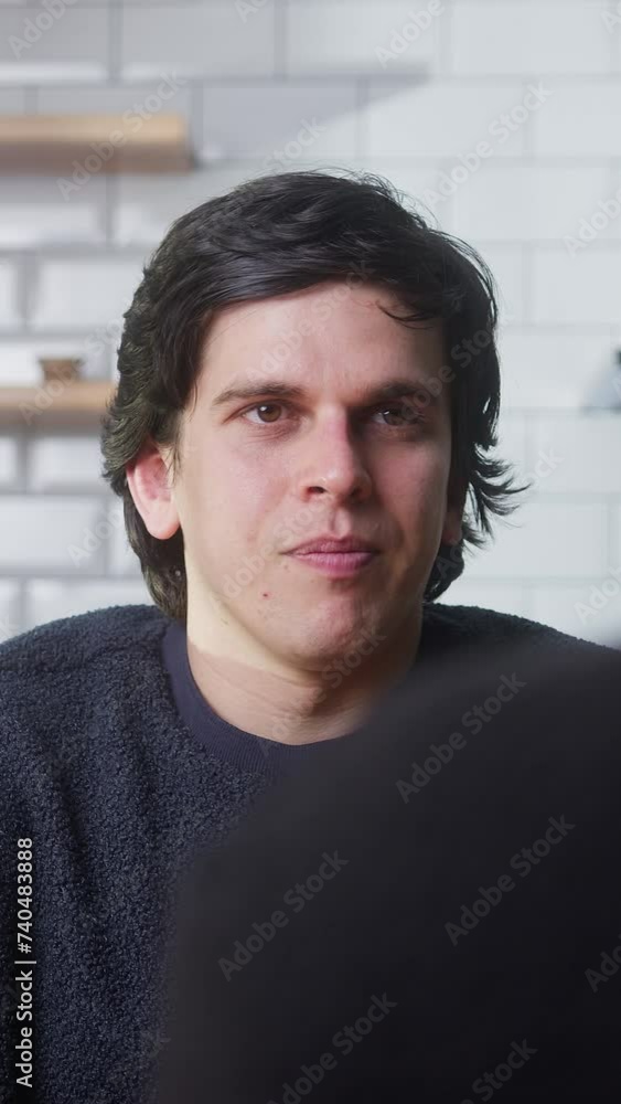 Vertical video. Two men are sitting in the kitchen having a fun chat ...