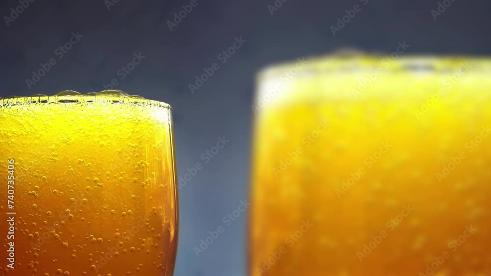 Orange soda is pouring into a two glasses with ice cubes on a white ...