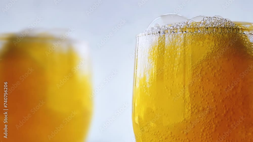 Vidéo Stock Orange soda is pouring into a two glasses with ice cubes on ...