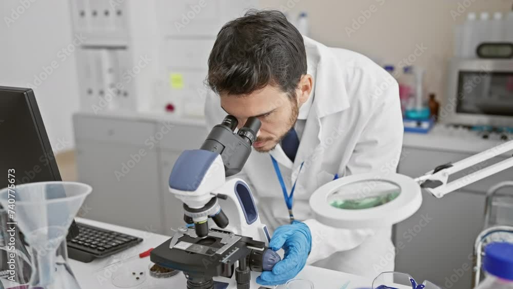 Hispanic scientist man with beard examines samples using a microscope ...