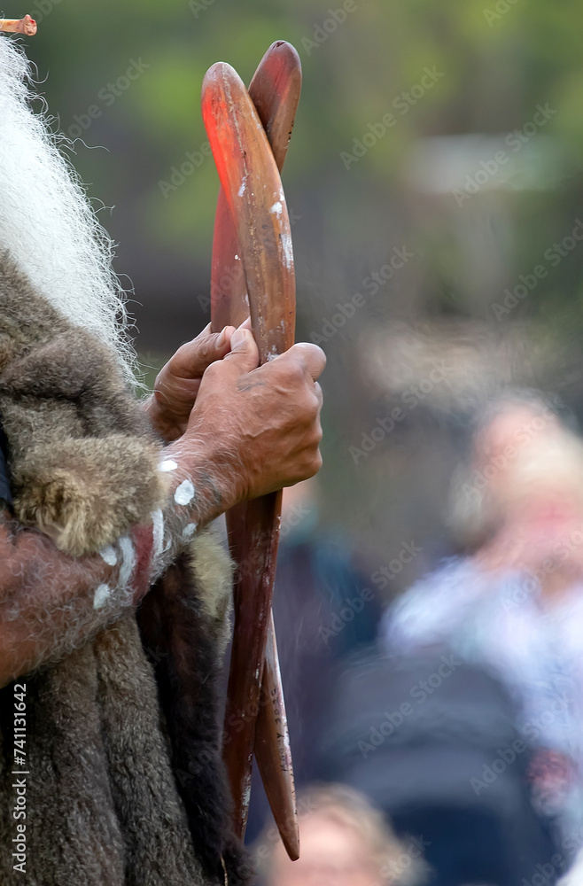 Human hand holds ritual clapsticks for the welcome ritual rite at an ...
