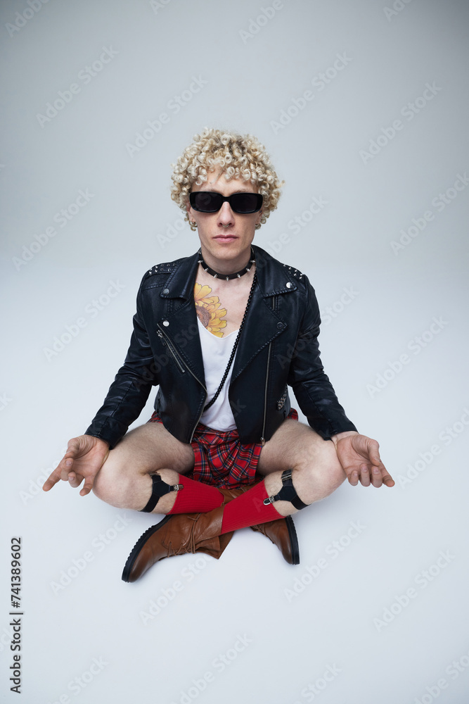 Man in leather jacket and kilt meditating, combining punk fashion with ...