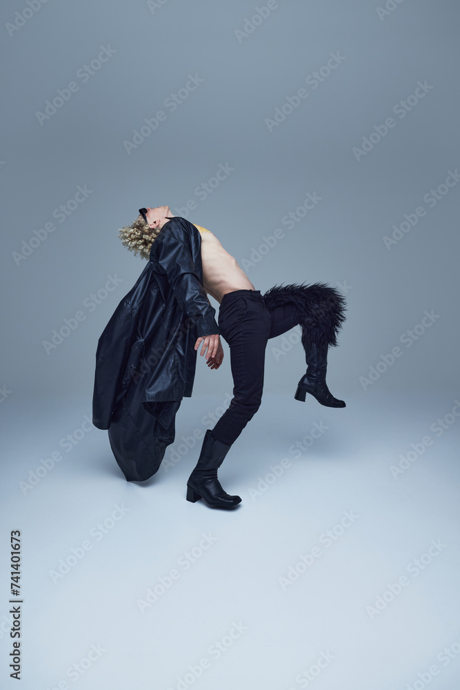 Shirtless man in black pants and heeled boots bending backward in ...