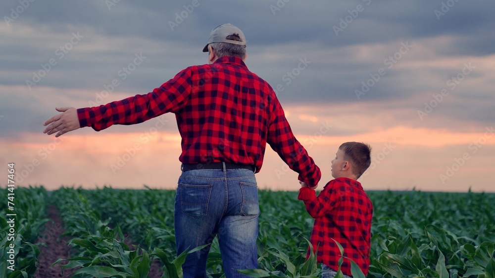 Foto de Farmer father working in green cornfield with child, son. Happy ...