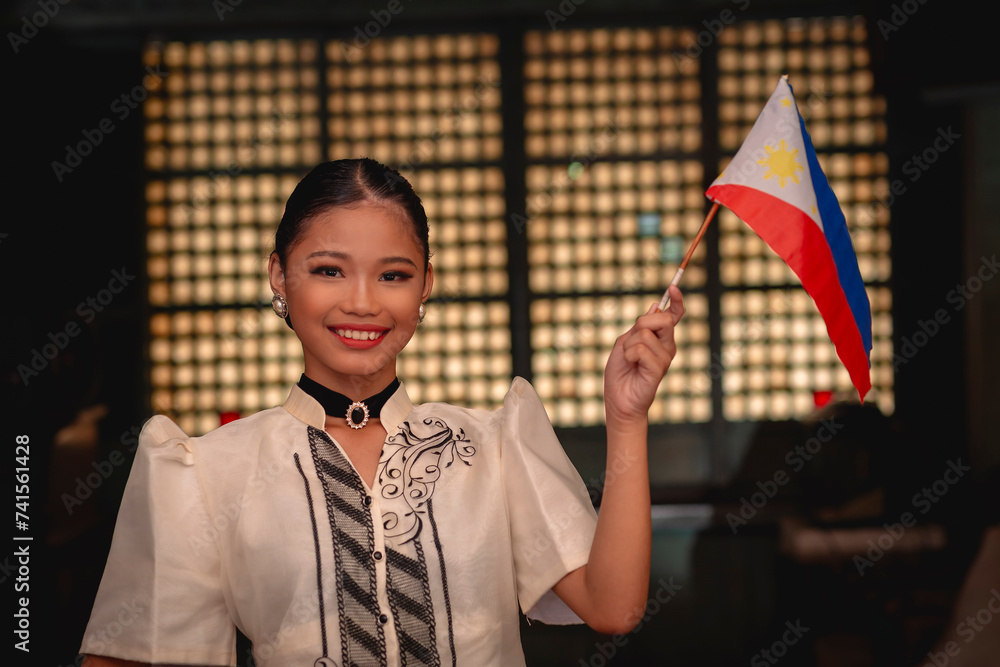 A proud young Filipina lady in a baro’t saya traditional dress, waving ...