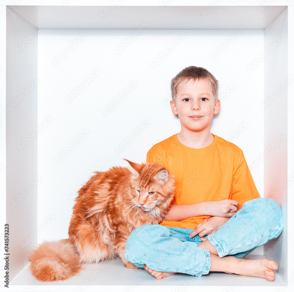 Cute boy sitting cross-legged on the floor with a Maine Coon cat on a ...
