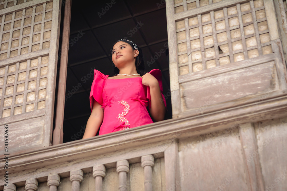 Candid shot of a young lady in a vibrant pink Filipiniana gown smiling ...