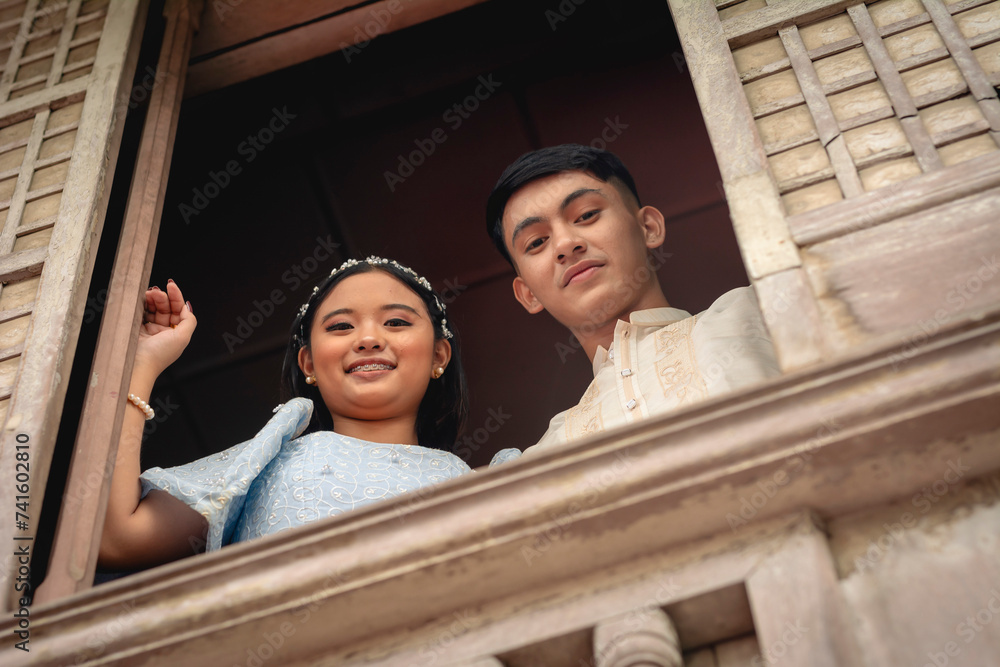 A young friendly couple in Filipino traditional clothing looking down ...