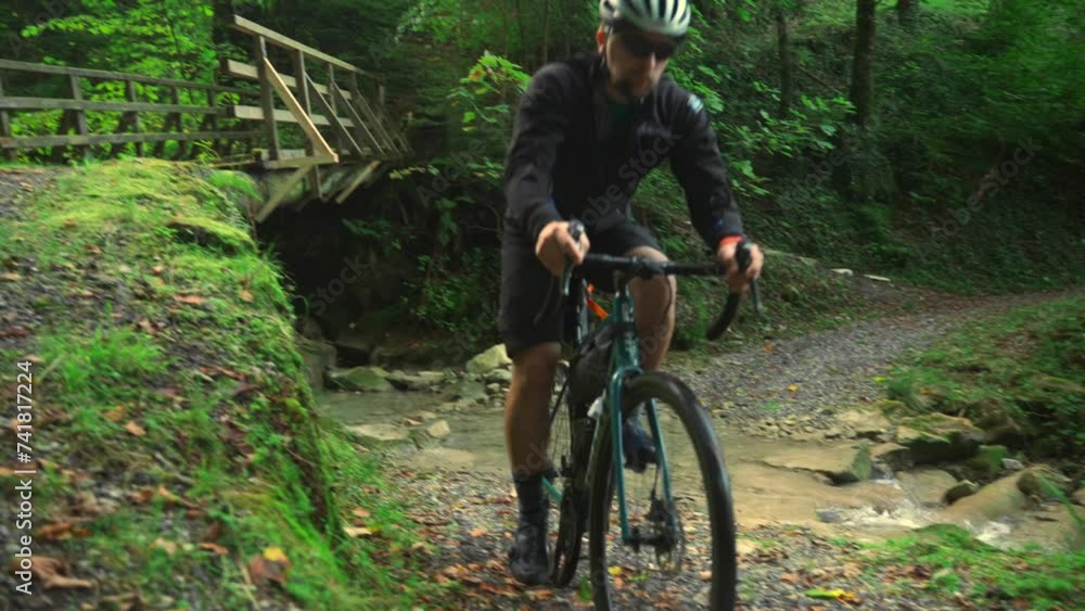 Male cyclist crossing river in mountains on gravel bicycle. Bicycle ...