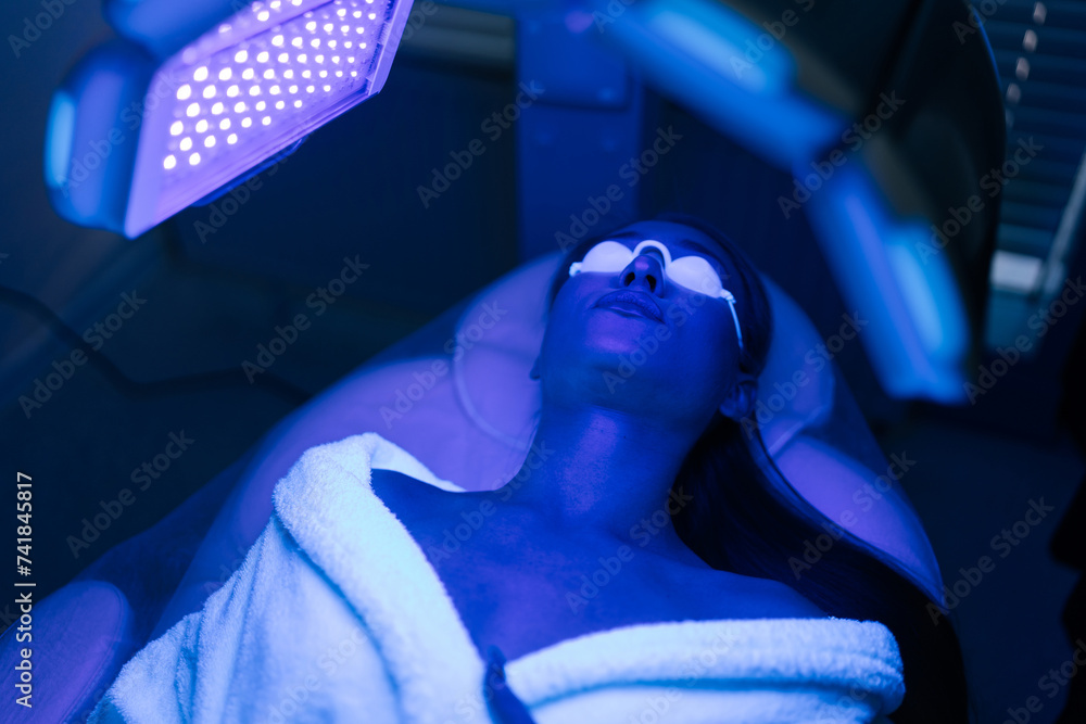 Closeup top view of female client having blue LED light facial ...