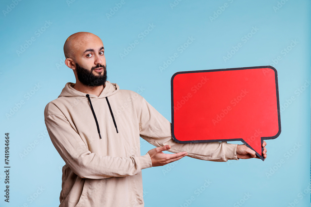 Arab man presenting product with empty speech bubble for promotional ...