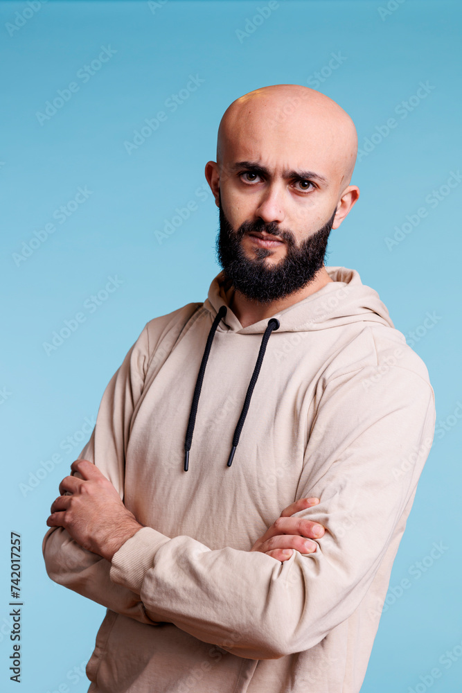 Serious arab man frowning eyebrows while posing with crossed arms ...