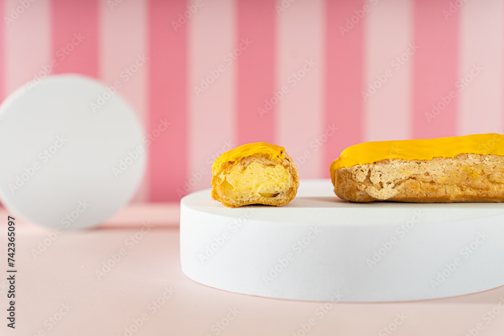 Eclair with mango custard and yellow icing on podium. Delicious eclair ...