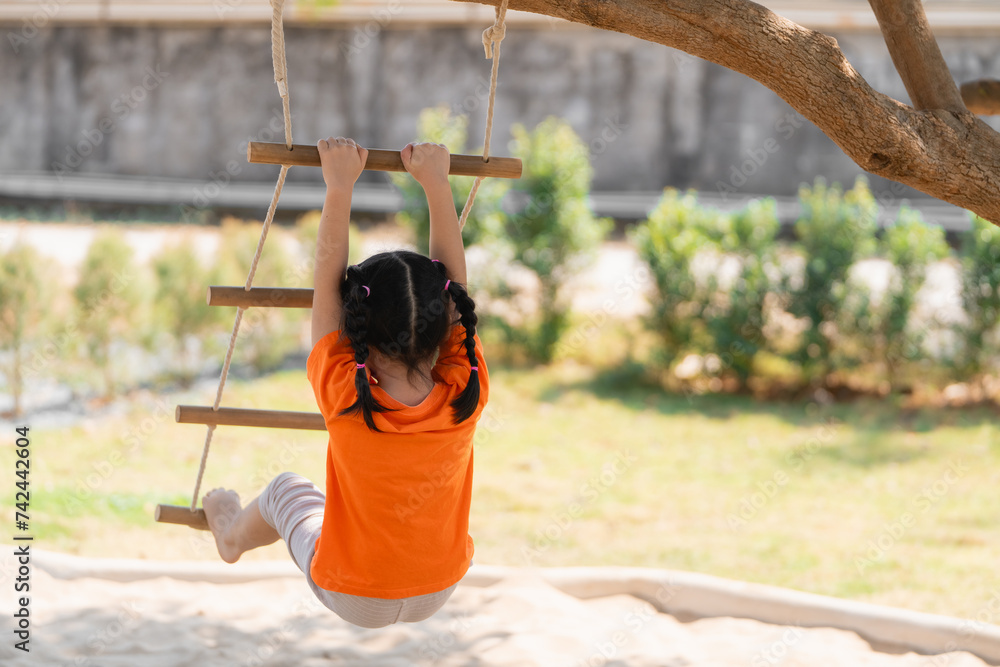 Back view. Young Girl Playing on a Rope Ladder. A little girl in an ...