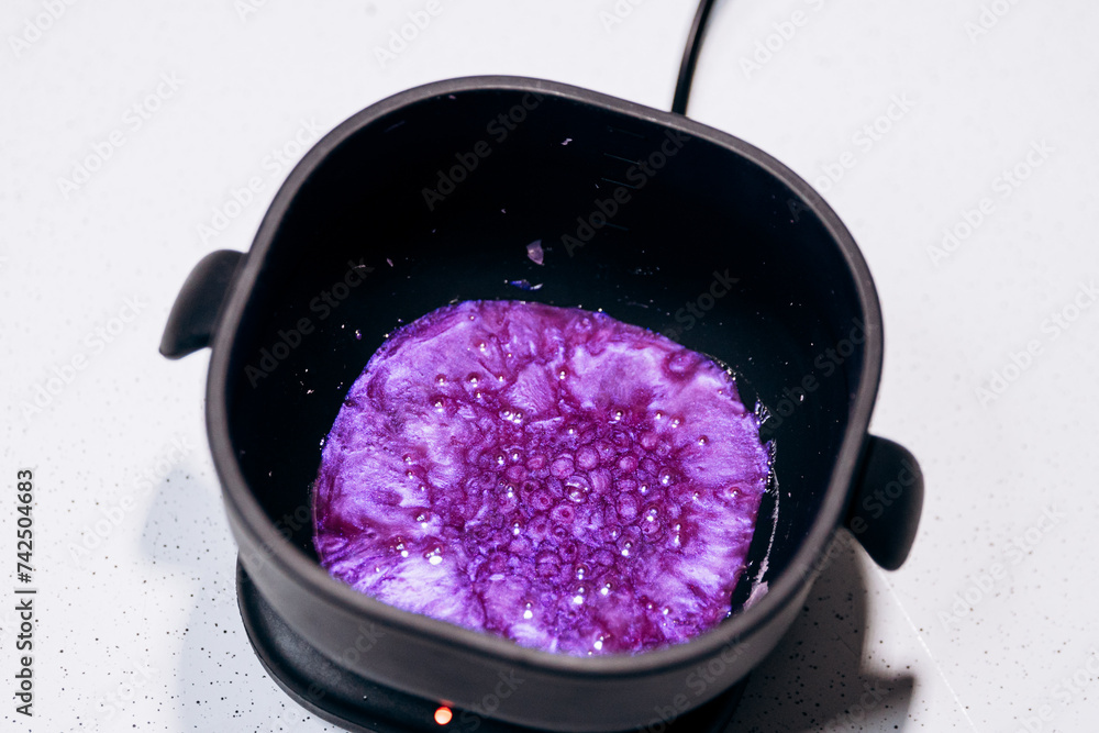 Purple granules are heated in a black wax melter. Eyebrow tools Stock ...