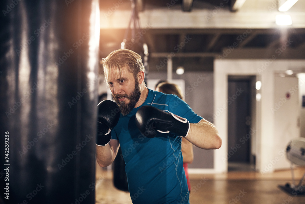 a fit and concentrated man sweating while practicing boxing on a ...