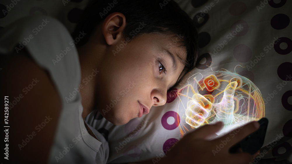 boy using smartphone at night lying in bed with one hand making ok ...