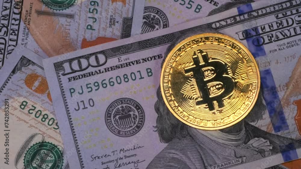 Bitcoin gold coin lies on the face of a 100 dollar bill rotating top ...