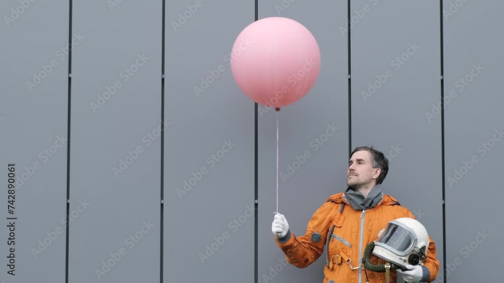 Hero astronaut wearing space suit holding pink helium balloon against ...