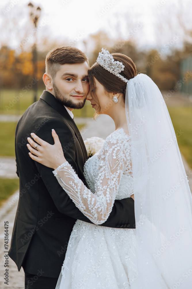 A young bride and groom tenderly embrace in the rays of the autumn sun ...