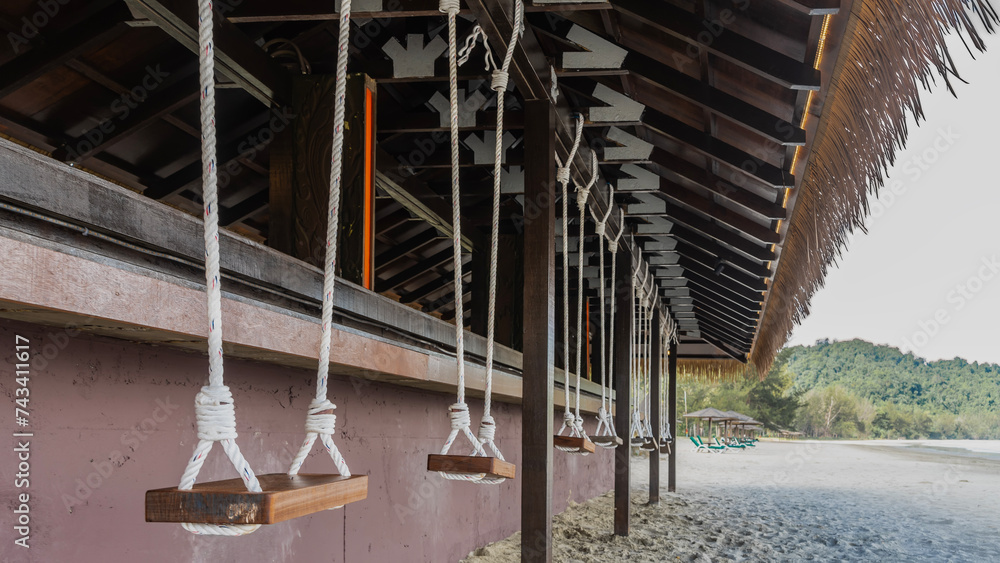 The beach bar is empty during the day. Wooden swing seats are suspended ...