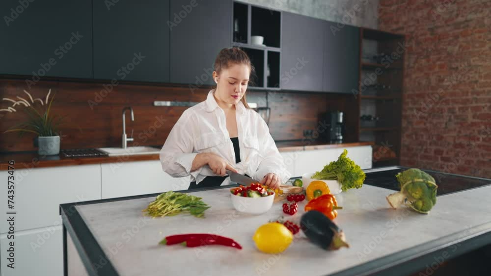Young woman cooking, dancing at kitchen. Female cook food listen to ...