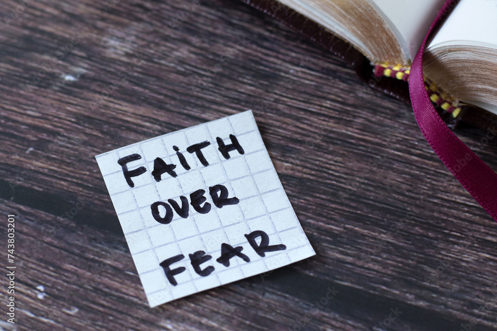 Faith over fear, handwritten text with open holy bible book on wood ...