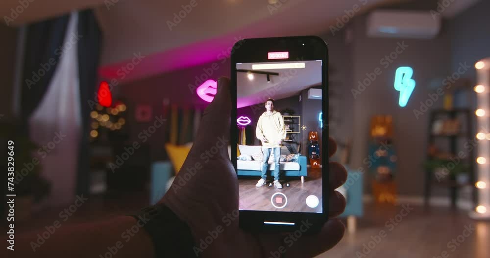 We look at the screen of mobile phone, where young TikToker performs ...