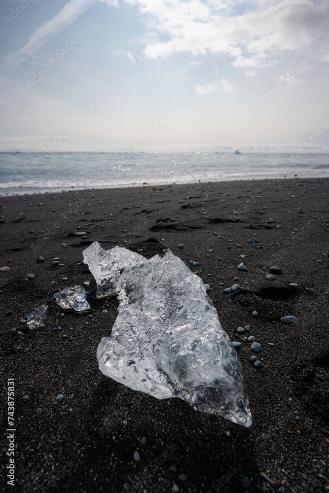 Ocean waves lapping up chunks of ice sparkling in the sun on a black ...