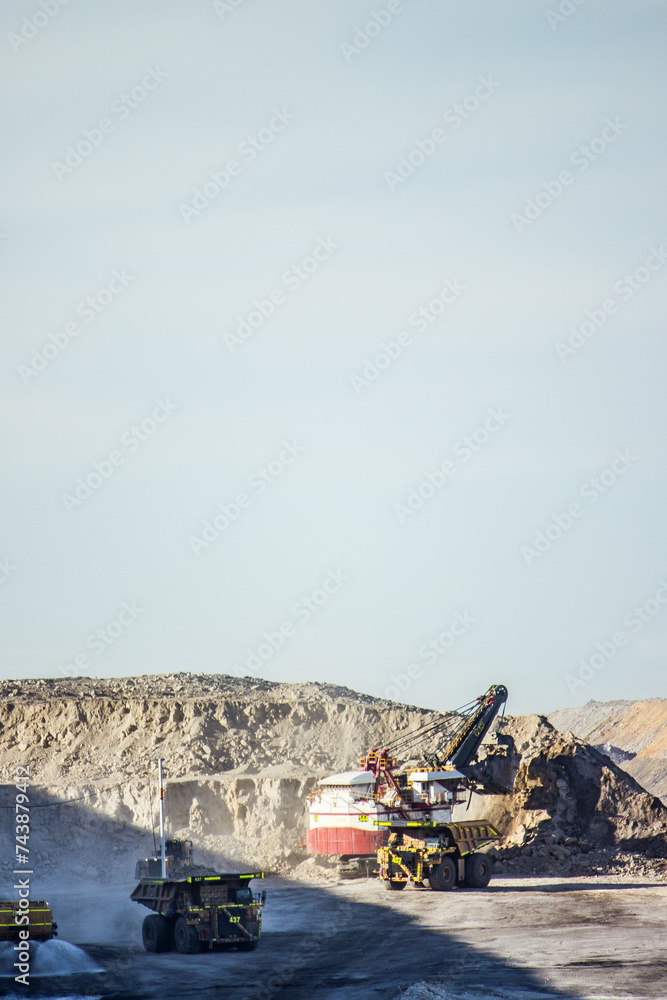Dump trucks filling up with overburden and carting it through open cut ...